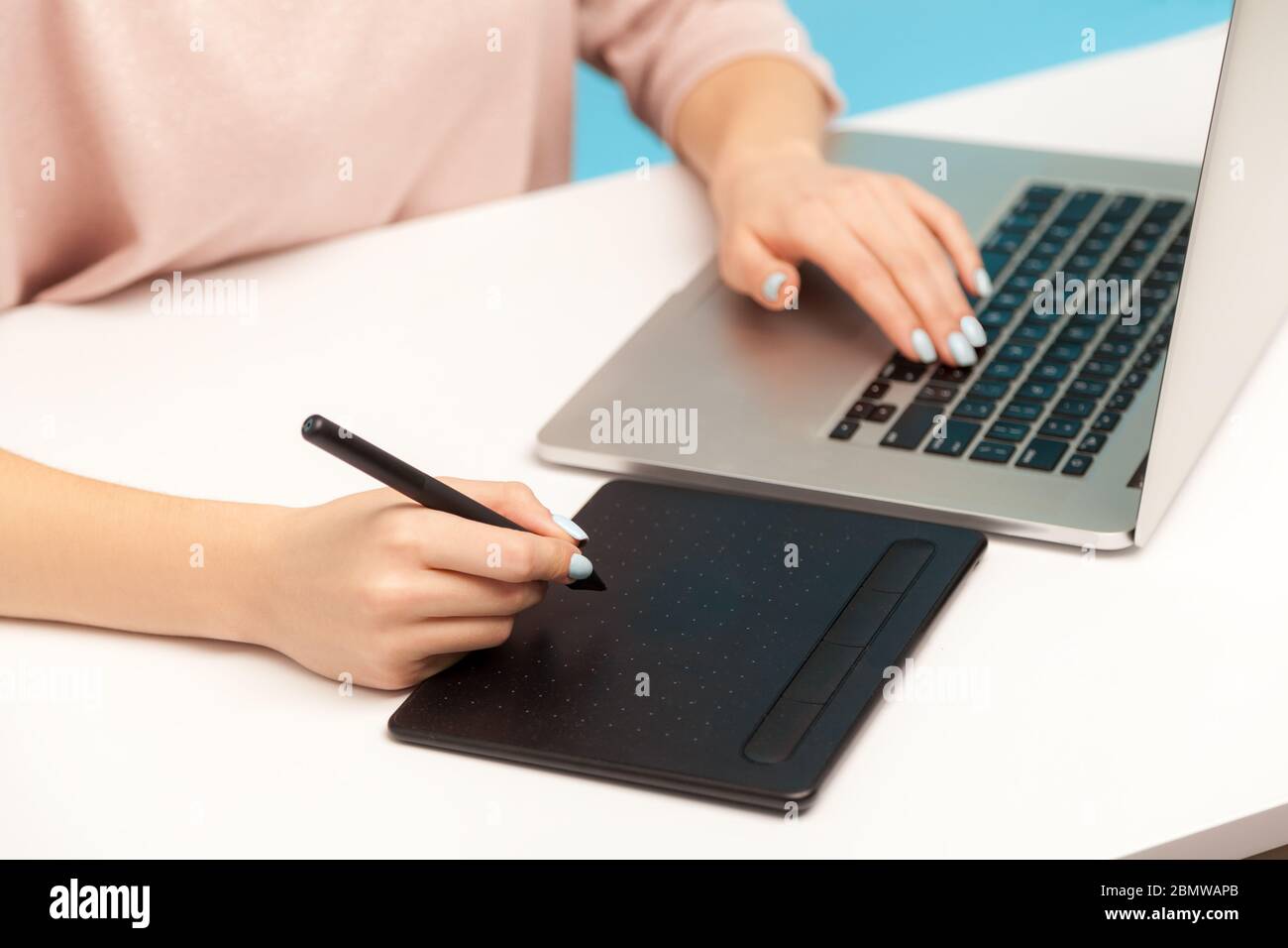 Closeup of woman designer hands working on graphic tablet and typing ...