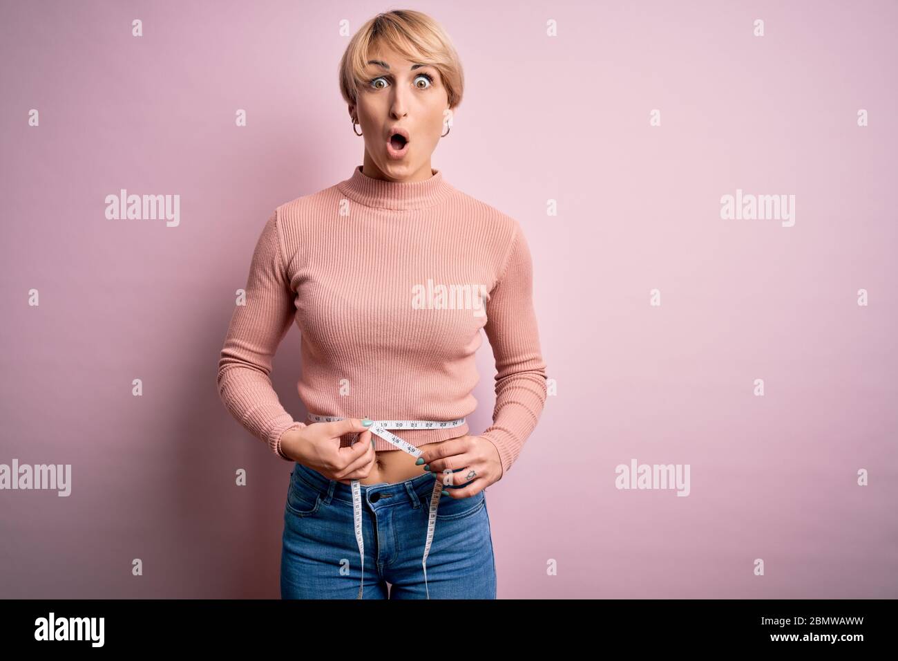 Young blonde thin woman with short hair measuring body figure using ...