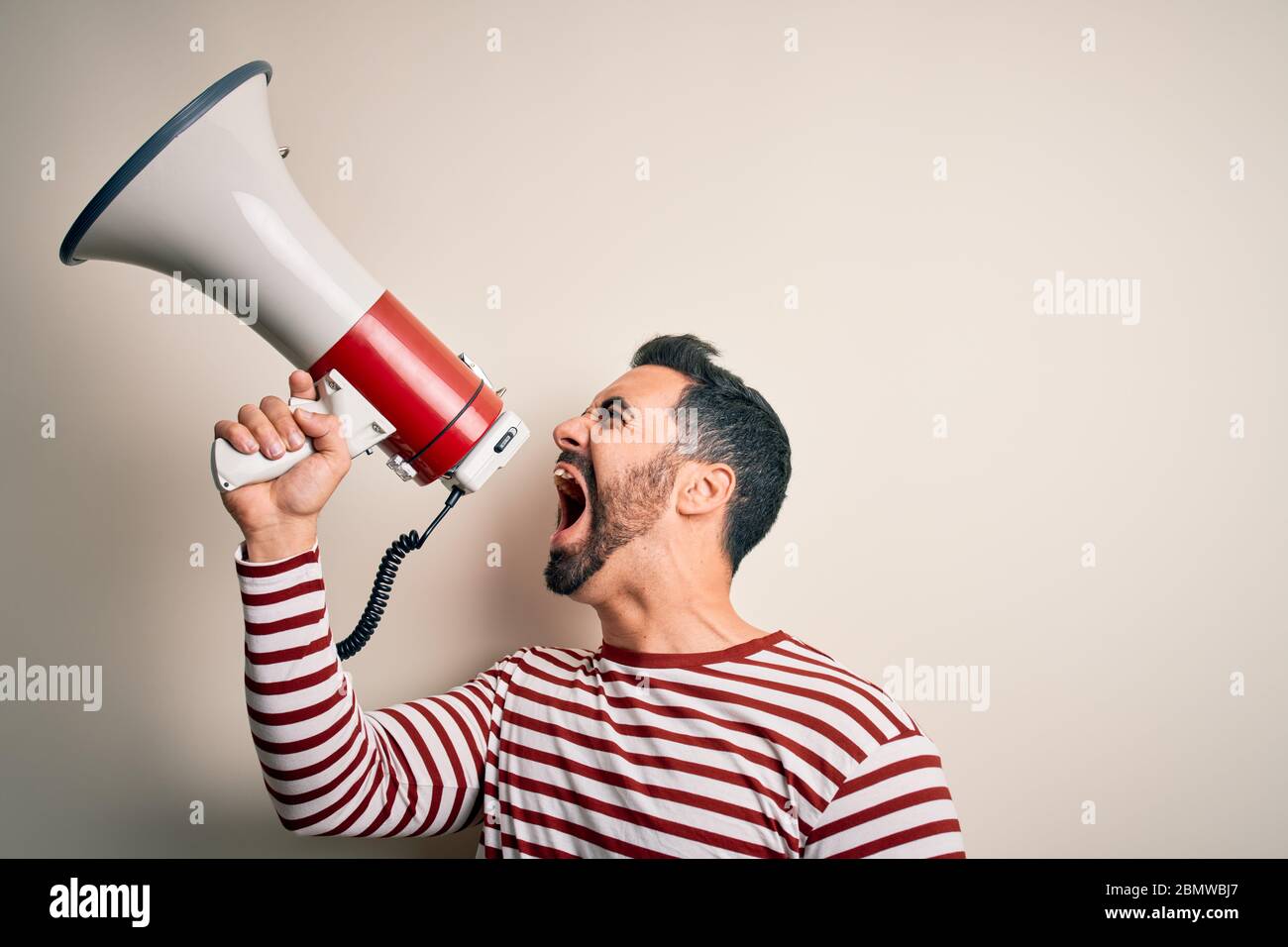 Hispanic man shouting angry on protest through megaphone. Yelling ...