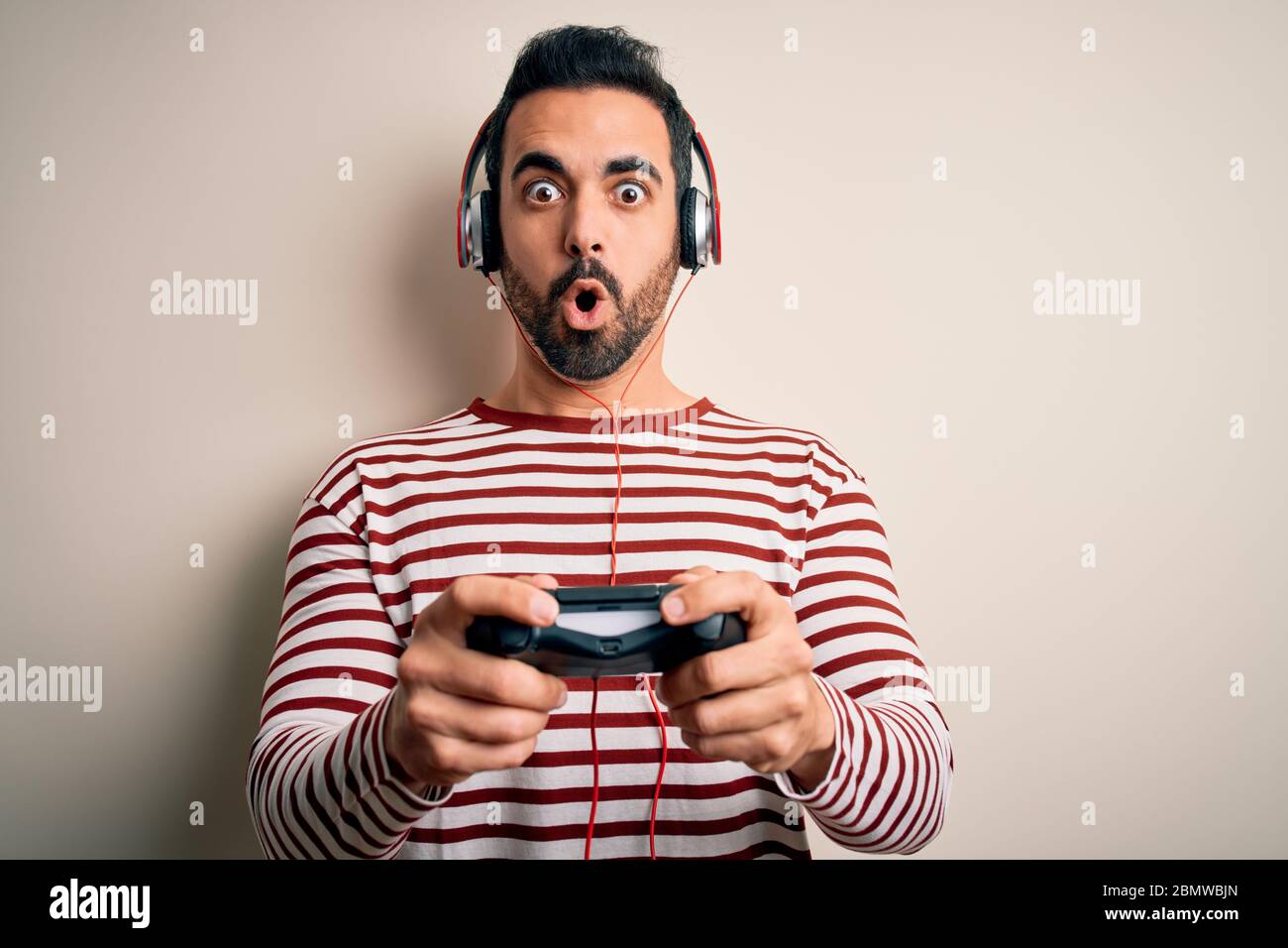 Young handsome gamer man with beard playing video game using joystick ...