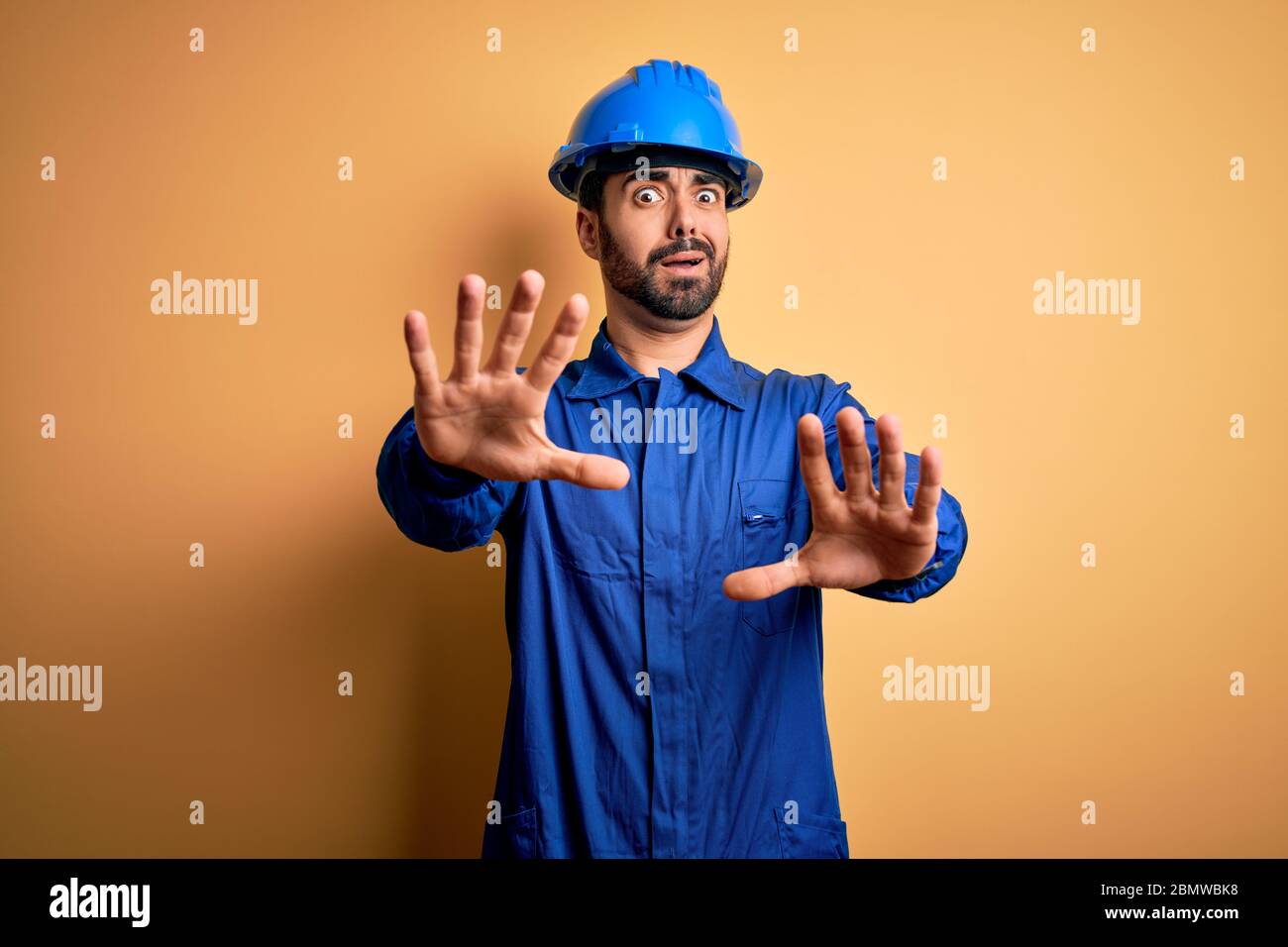 Mechanic man with beard wearing blue uniform and safety helmet over ...