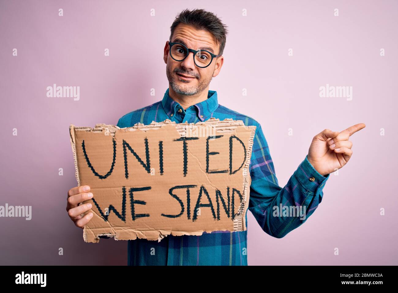 Young handsome activist man asking for union holding banner with united ...