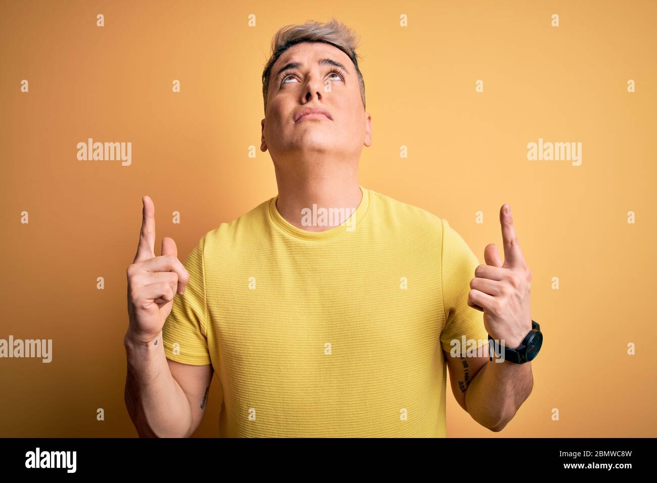 Young handsome modern man wearing yellow shirt over yellow isolated ...