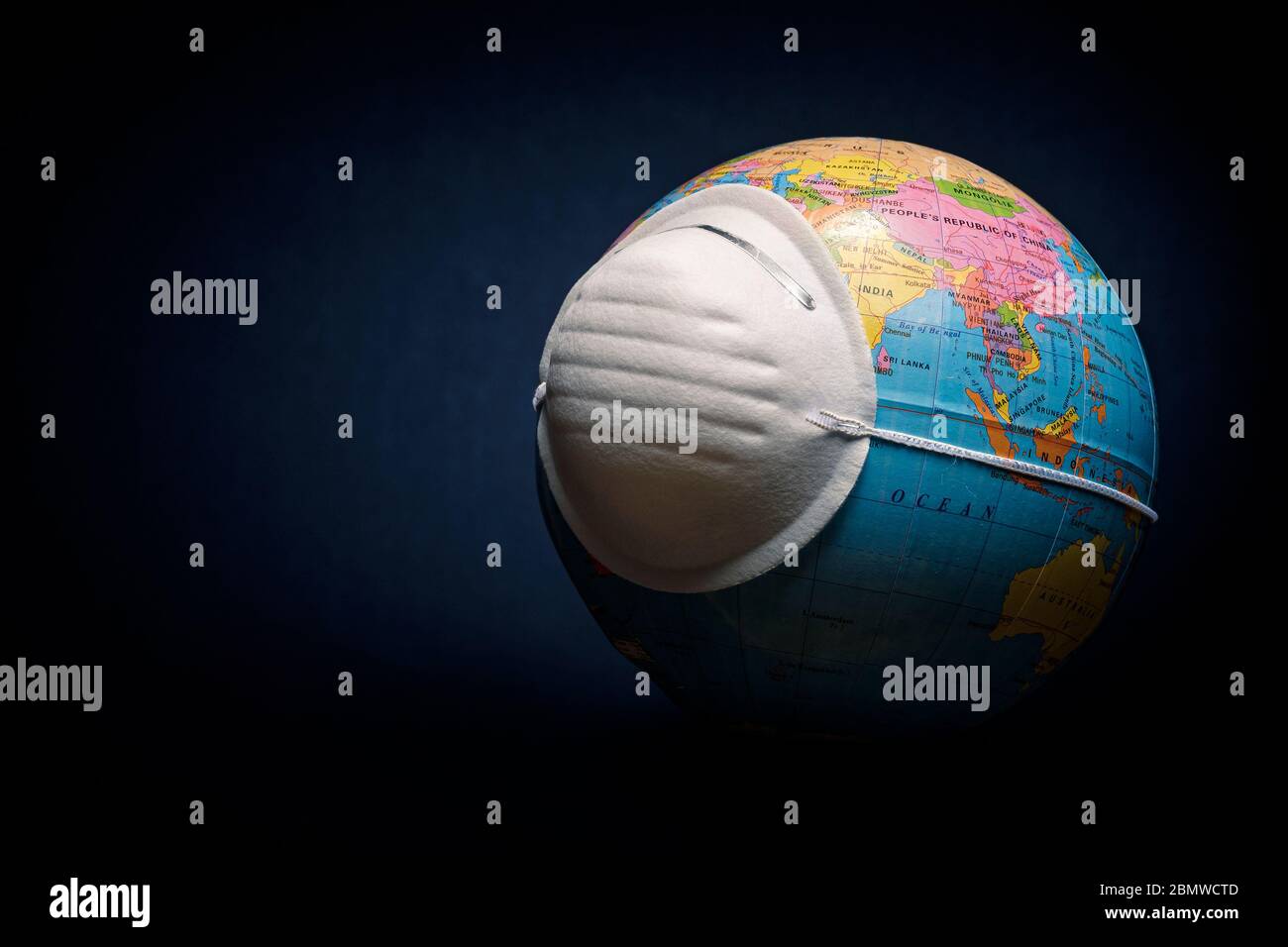 World globe wearing a protective face mask in side view on a black ...