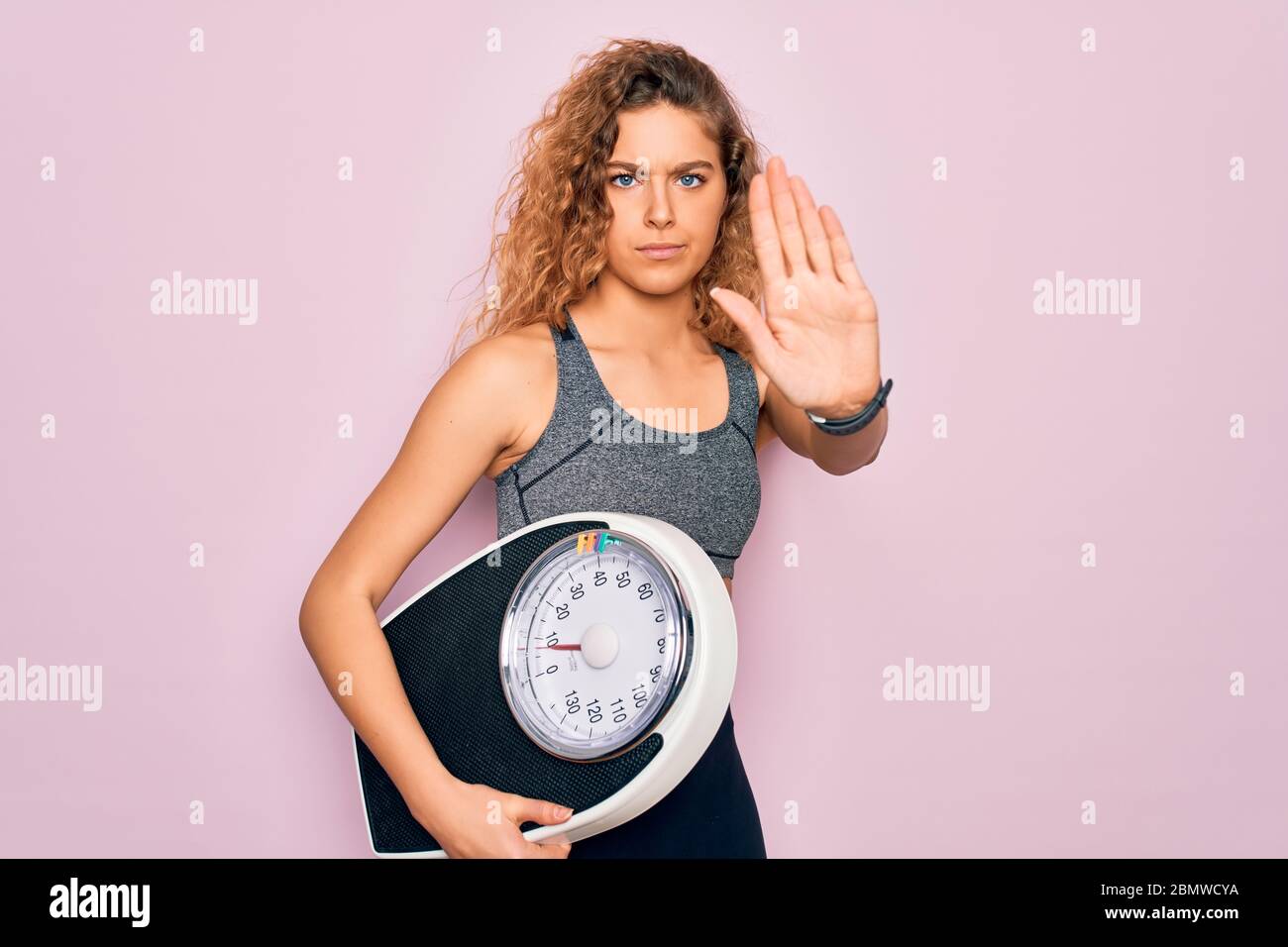 Young beautiful slim sporty woman with blue eyes controlling weight ...