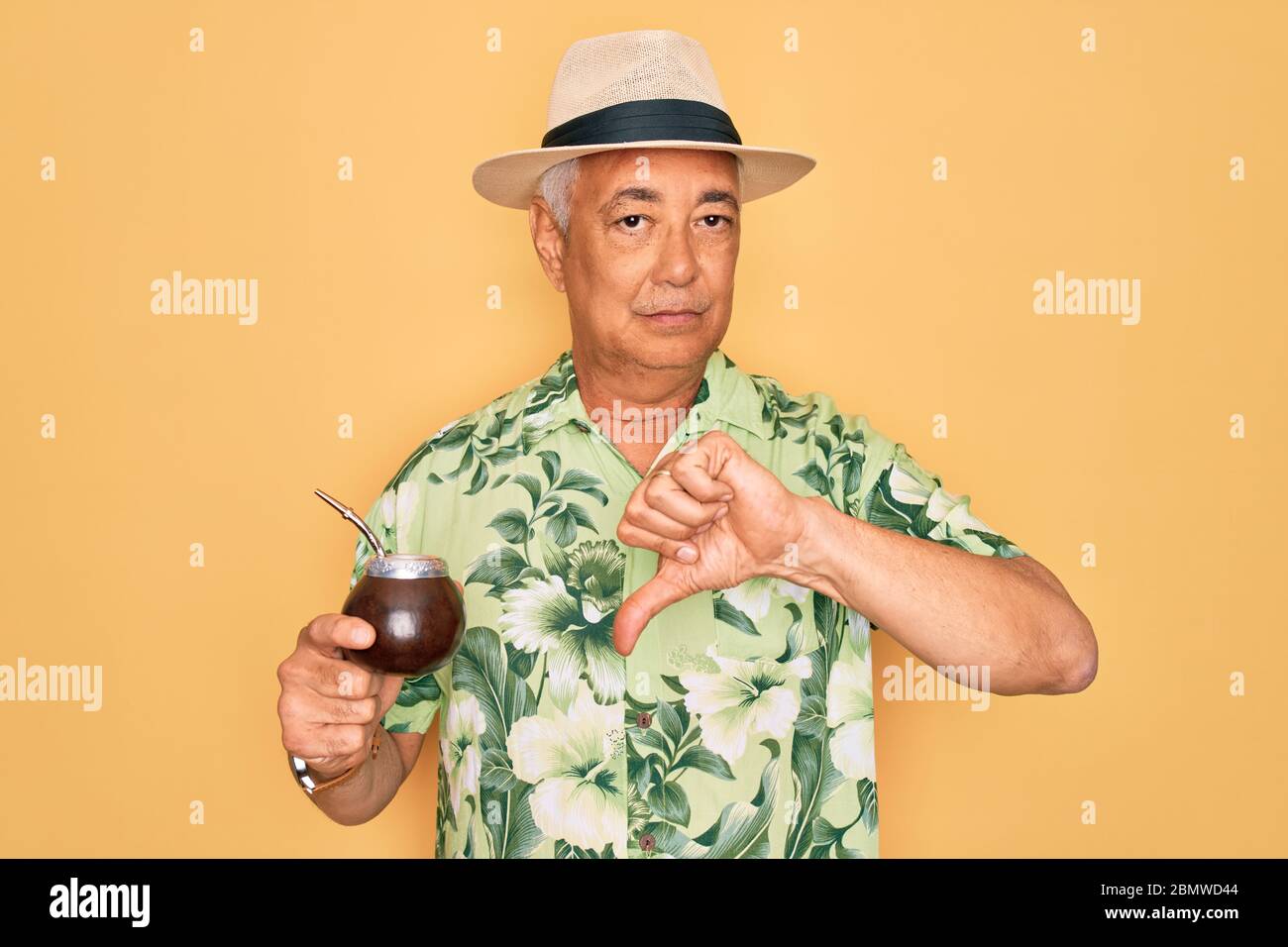 Middle age senior grey-haired man wearing summer hat drinking ...