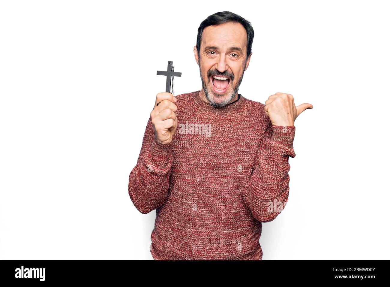 Middle age handsome catholic man praying holding christian cross over ...