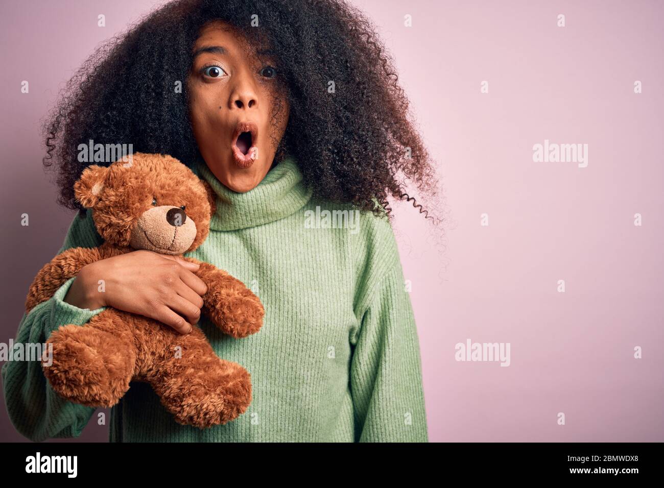 Young african american woman with afro hair hugging teddy bear over ...