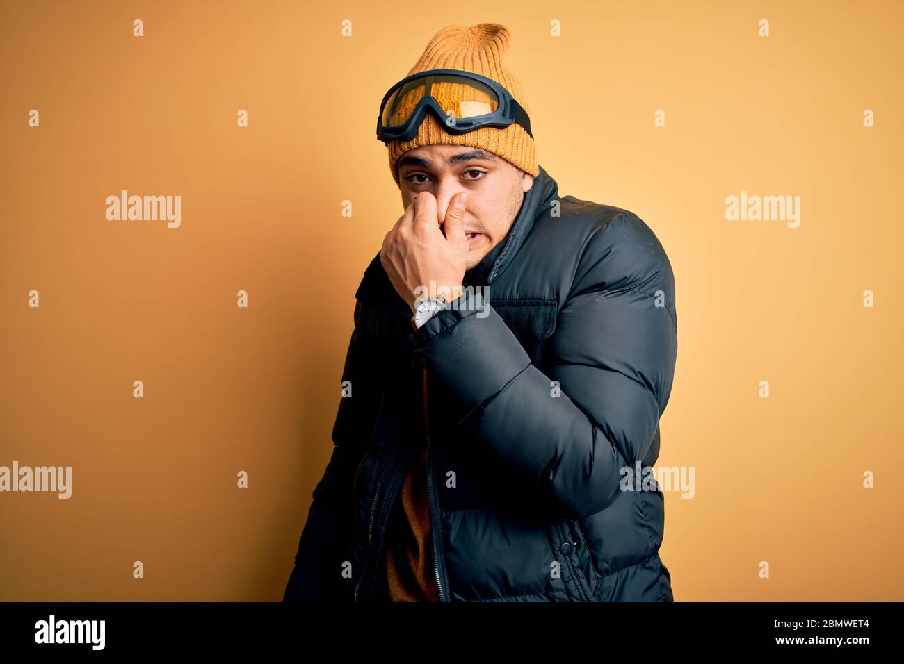 Young brazilian skier man wearing snow sportswear and ski goggles over ...