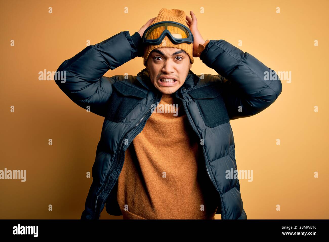 Young brazilian skier man wearing snow sportswear and ski goggles over ...