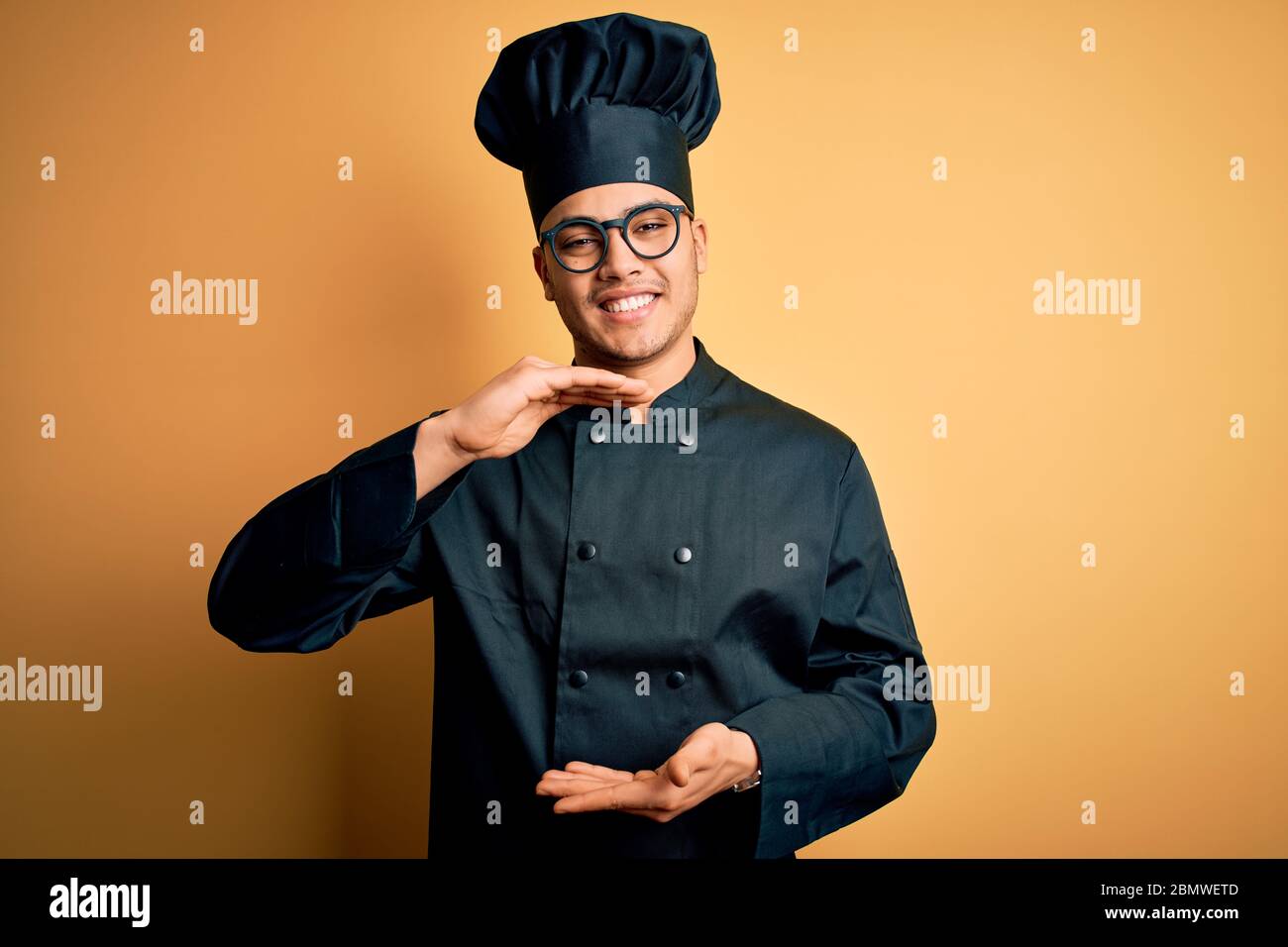 Young brazilian chef man wearing cooker uniform and hat over isolated ...