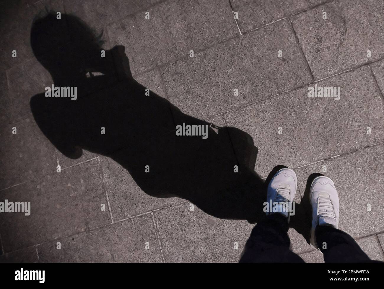 When looking down at the shadow of a woman on a concrete road. Diagonal ...