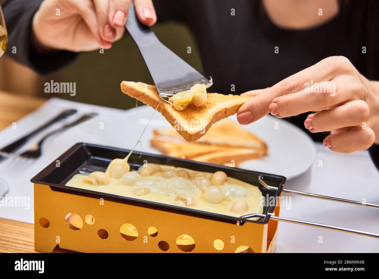 woman eat swiss food. cheese raclette with mushrooms on coupelles ...