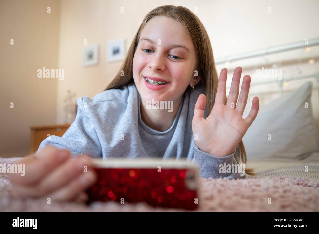 Smiling Teenage Girl In Bedroom Talking With Friends On Social Media ...