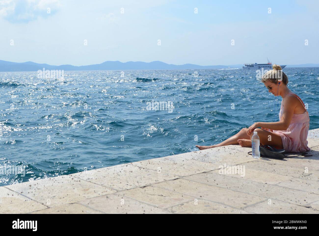 Tourist enjoying the Adriatic sea views from the Nova Riva promenade in ...
