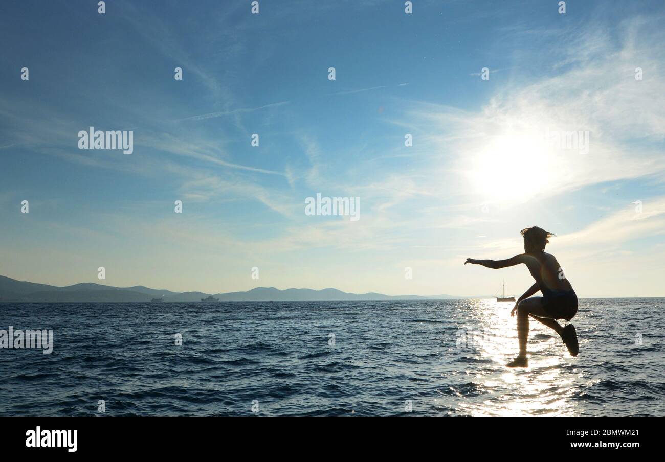 A boy jumping into the Adriatic sea from the promenade in Zadar ...