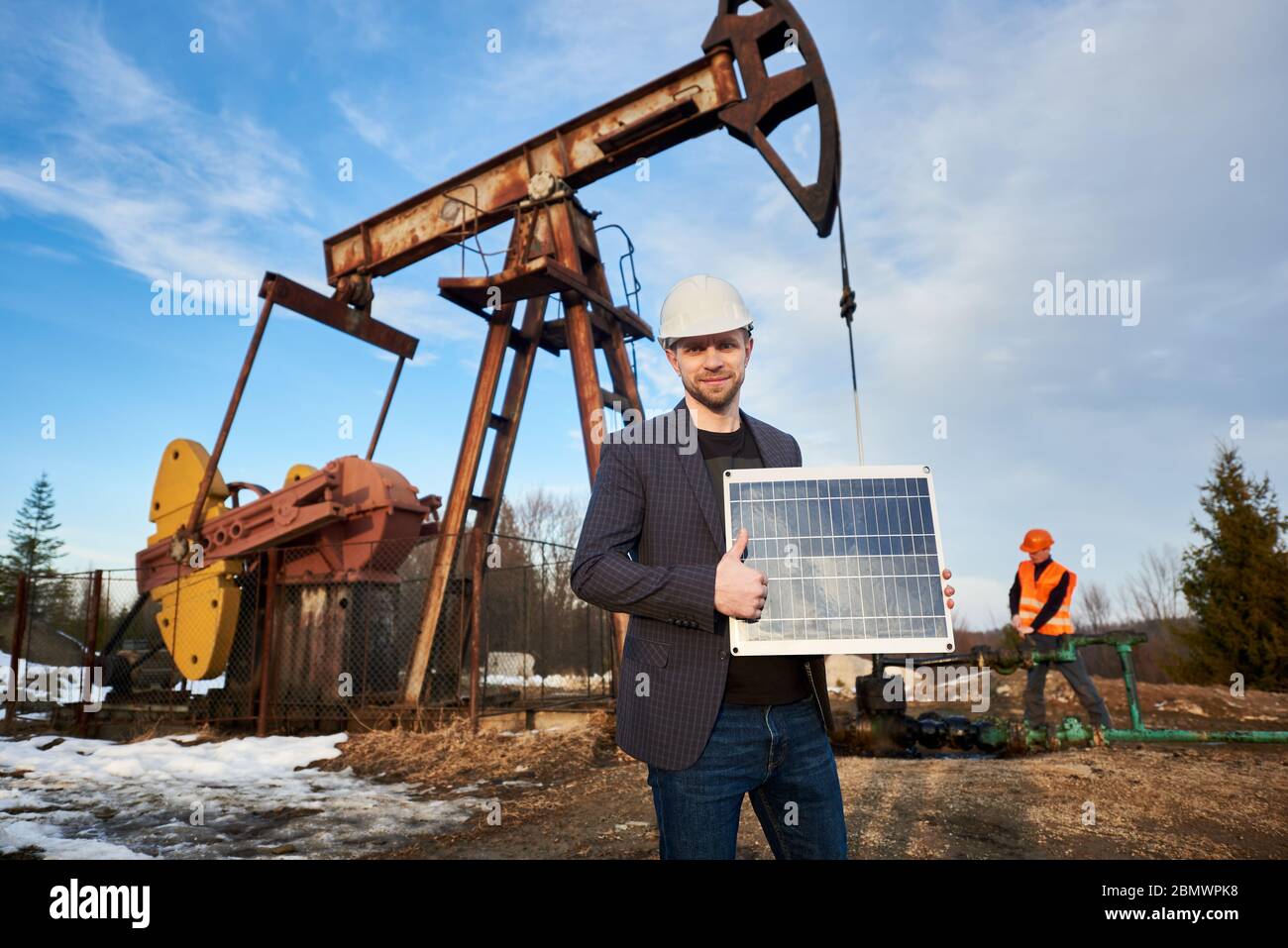 Portrait of businessman in suit jacket, helmet, holding mini solar ...