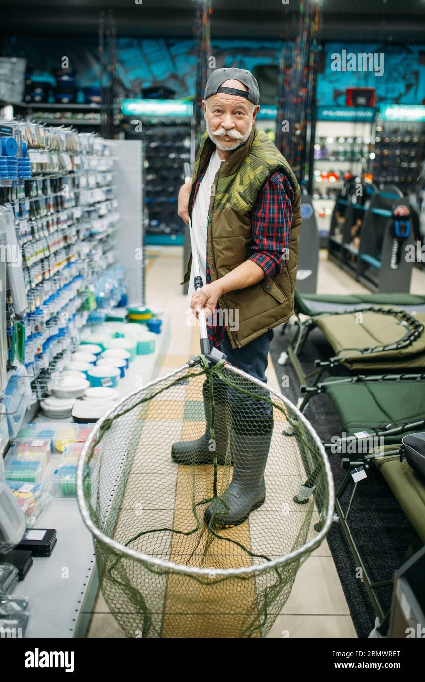 Happy angler holds net in fishing shop Stock Photo - Alamy