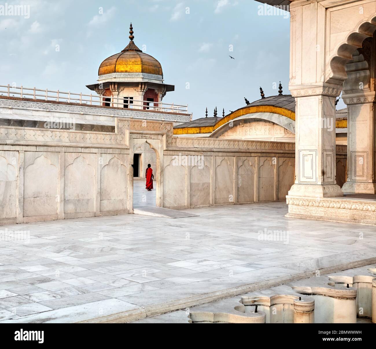 Indian woman in red sari is walking in Agra Fort at blue sky in India ...