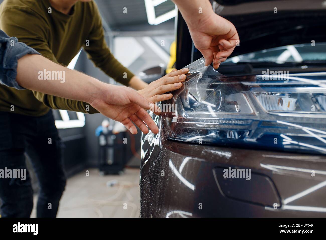 Workers applies car protection film on fender Stock Photo - Alamy