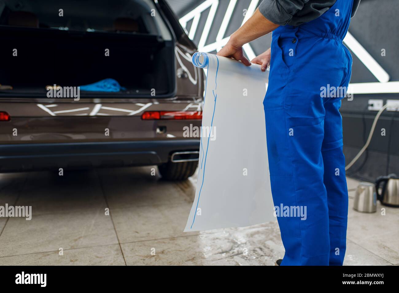 Male worker holds roll of car protection film Stock Photo - Alamy