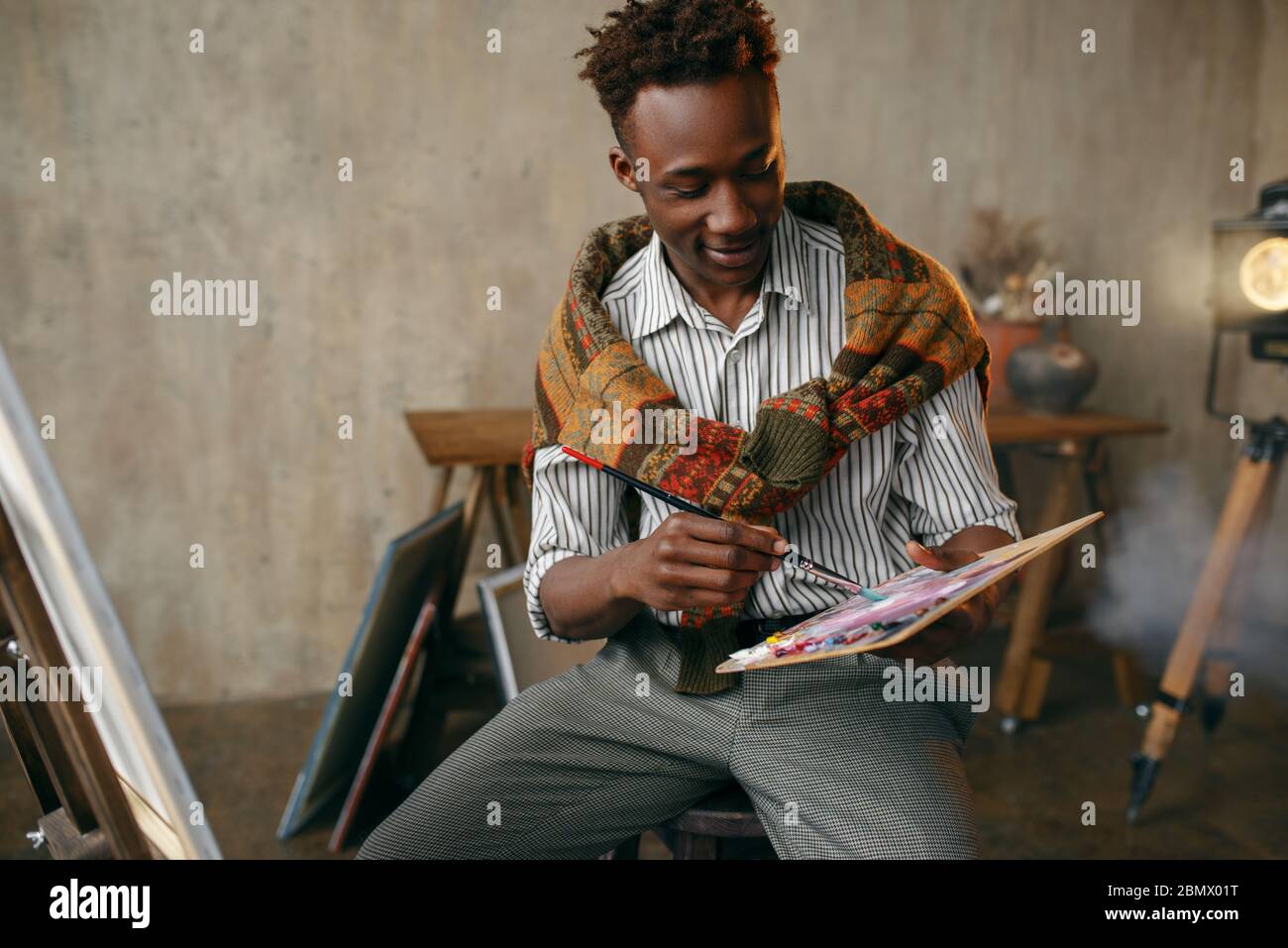 Smiling painter with brush and palette at easel Stock Photo - Alamy