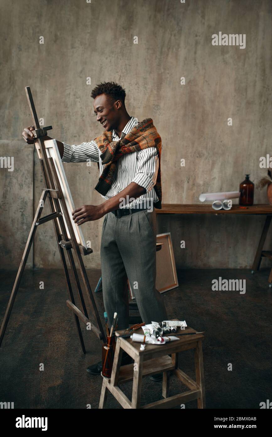 Happy painter prepares easel with canvas Stock Photo - Alamy