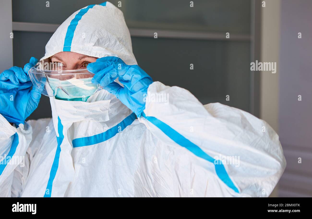 Doctor or nurse in protective clothing with safety glasses in clinic ...