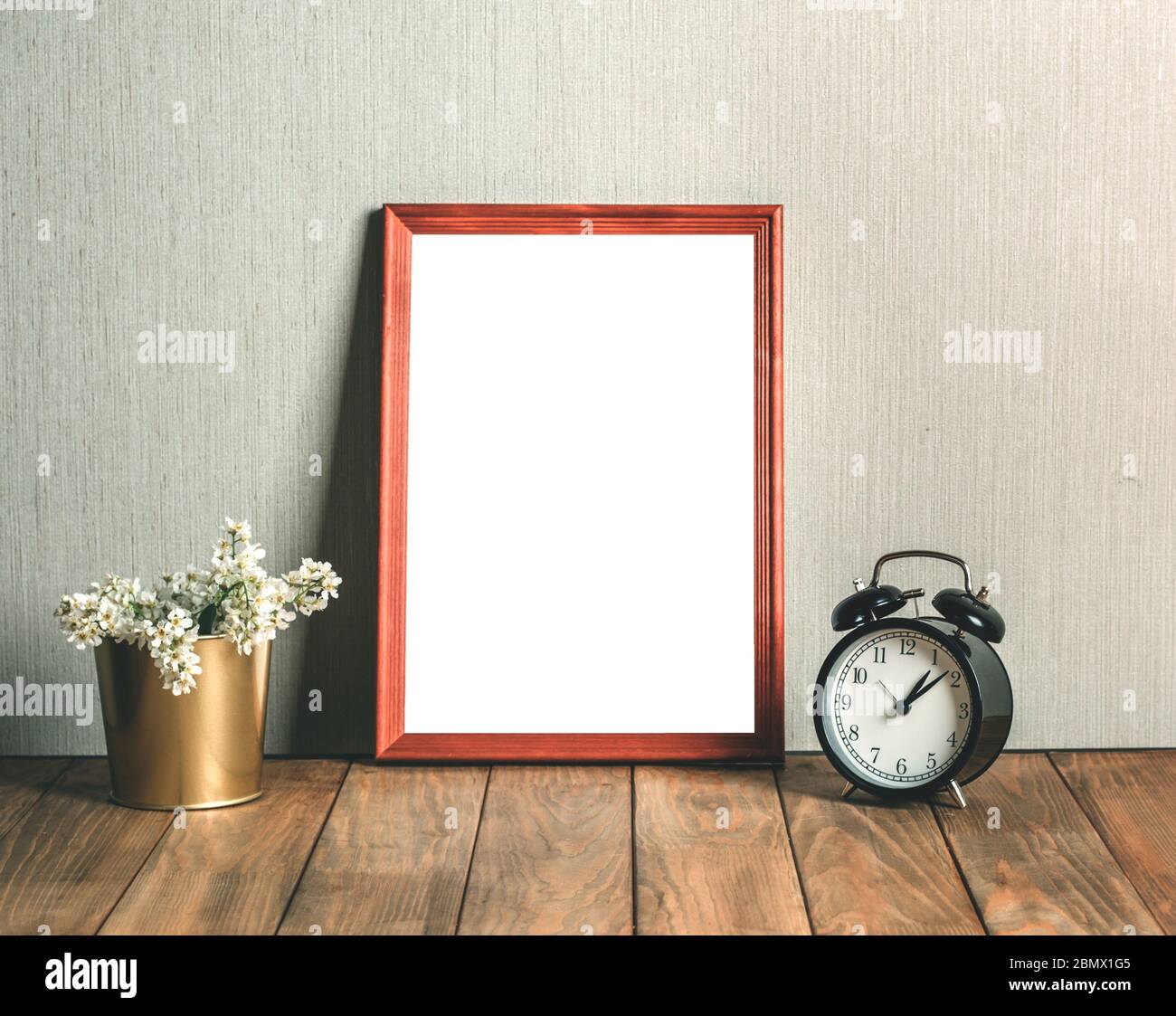 Wooden frame on the table with a bunch of white flowers and a clock ...