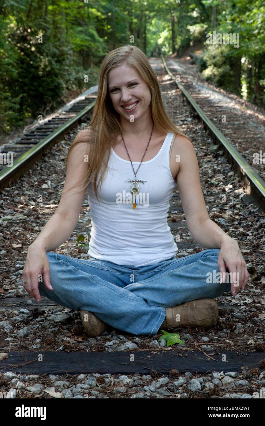Pretty Blond sitting on Railroad Tracks with a smile Stock Photo - Alamy