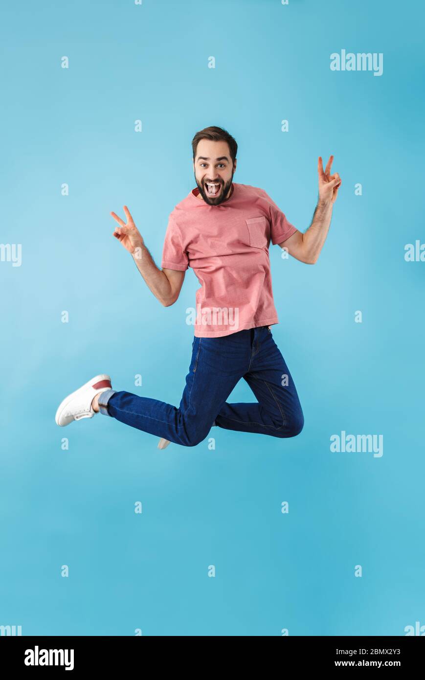 Image of young handsome excited happy man jumping isolated over blue ...
