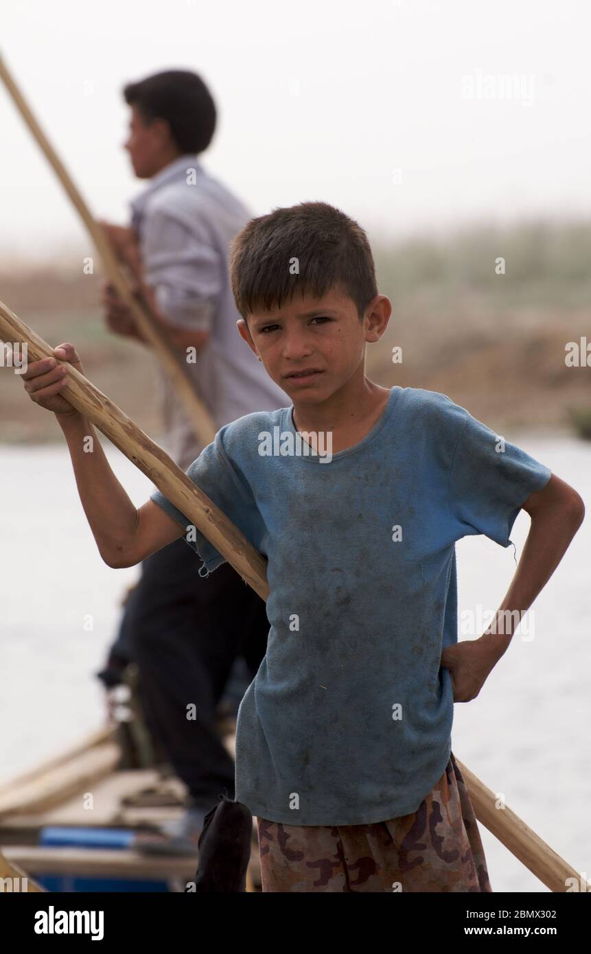 A young Marsh Arab boy holds a pole used for propelling his mashoof (a ...