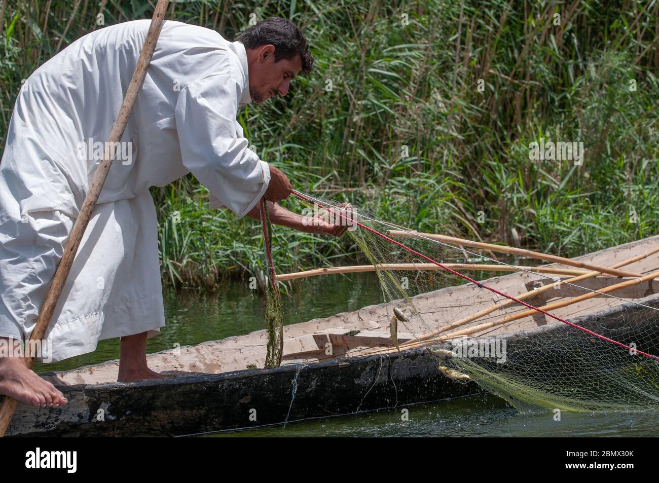 A Marsh Arab fisherman balances on his traditional boat (Mashoof ...