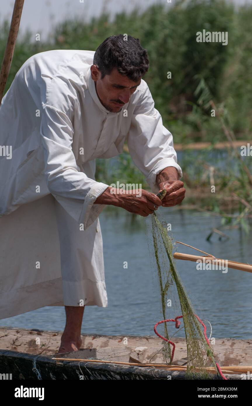 A Marsh Arab fisherman balances on his traditional boat (Mashoof ...