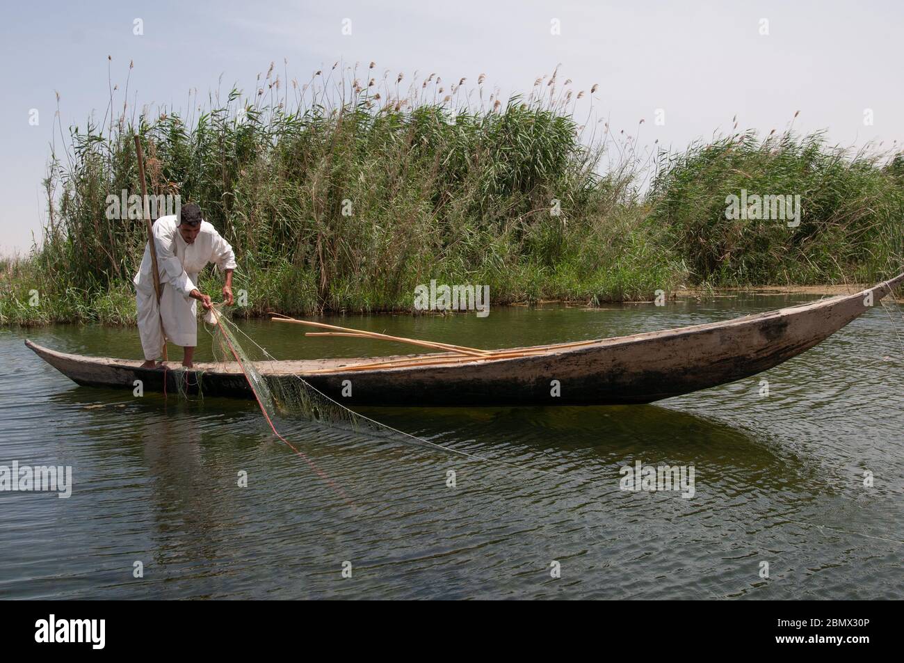 A Marsh Arab fisherman balances on his traditional boat (Mashoof ...