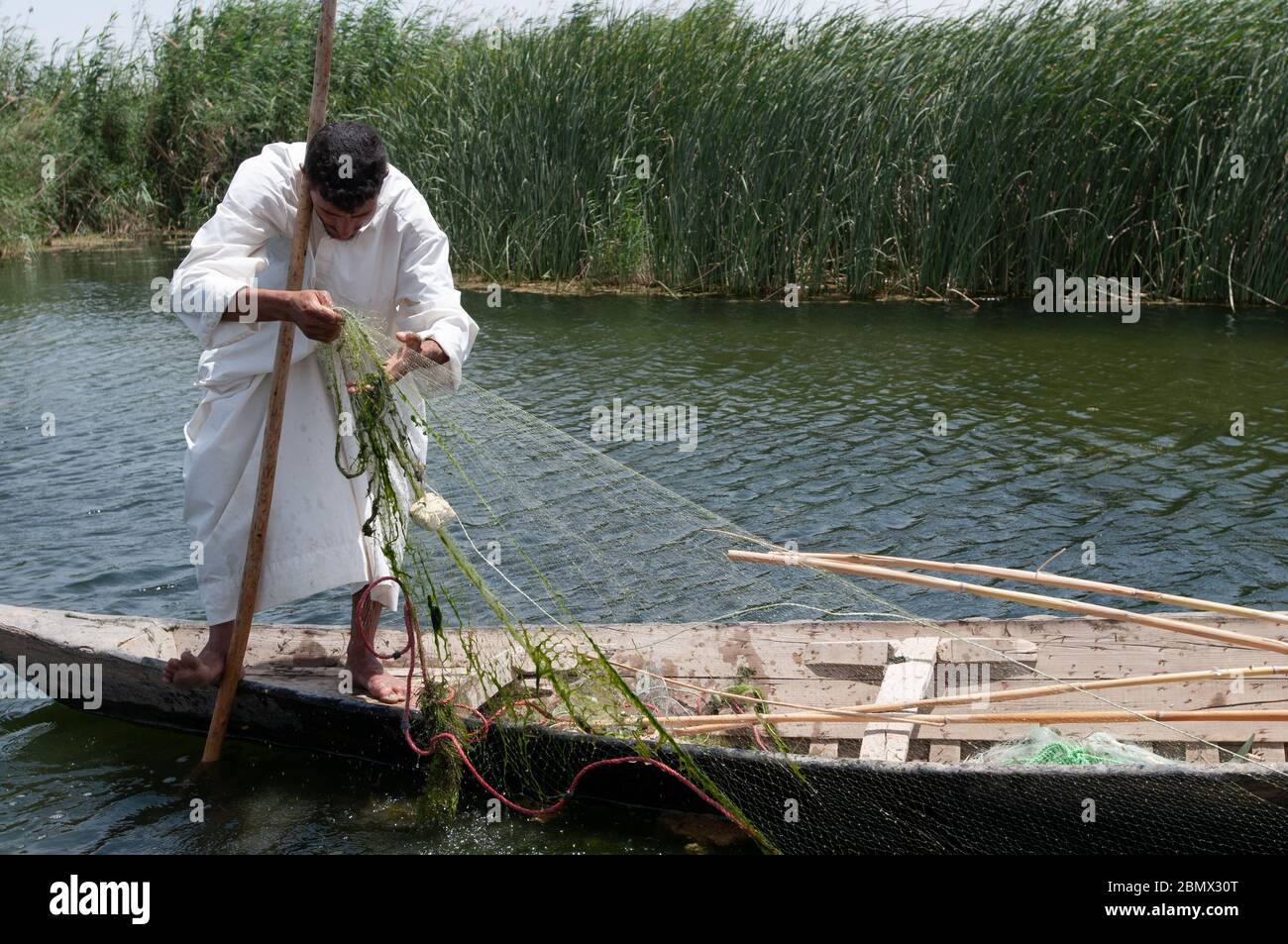 A Marsh Arab fisherman balances on his traditional boat (Mashoof ...
