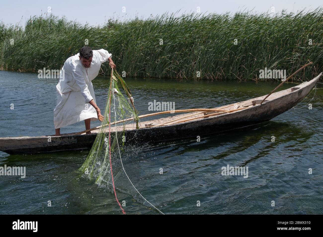 A Marsh Arab fisherman balances on his traditional boat (Mashoof ...