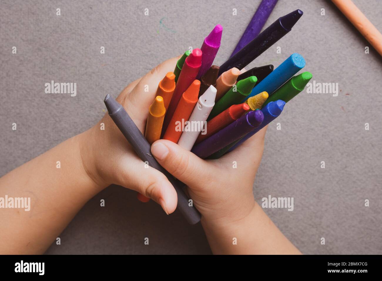 Closeup of child's hands with colorful wax crayons pencils. learning ...