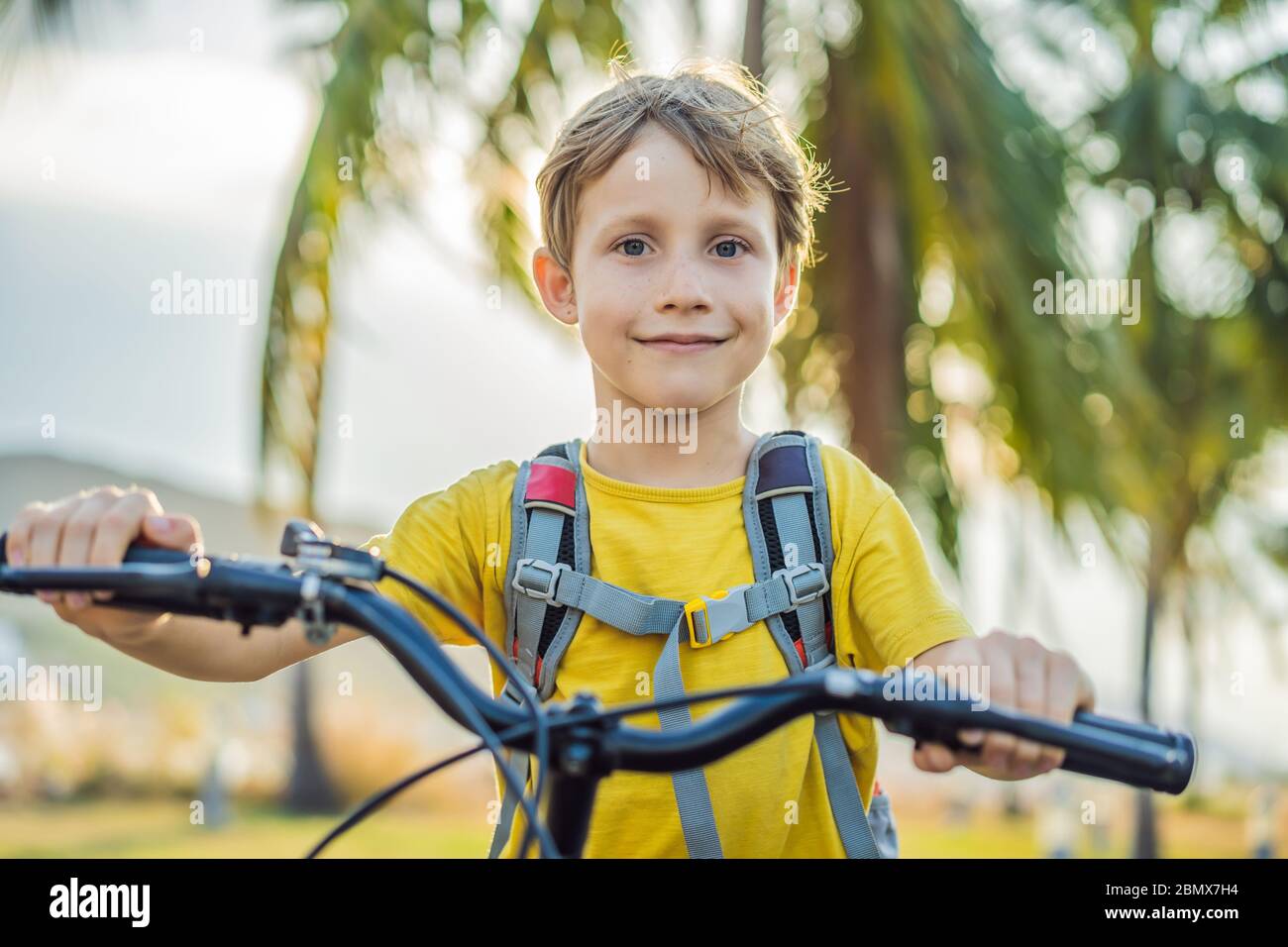 Active school kid boy riding a bike with backpack on sunny day. Happy ...