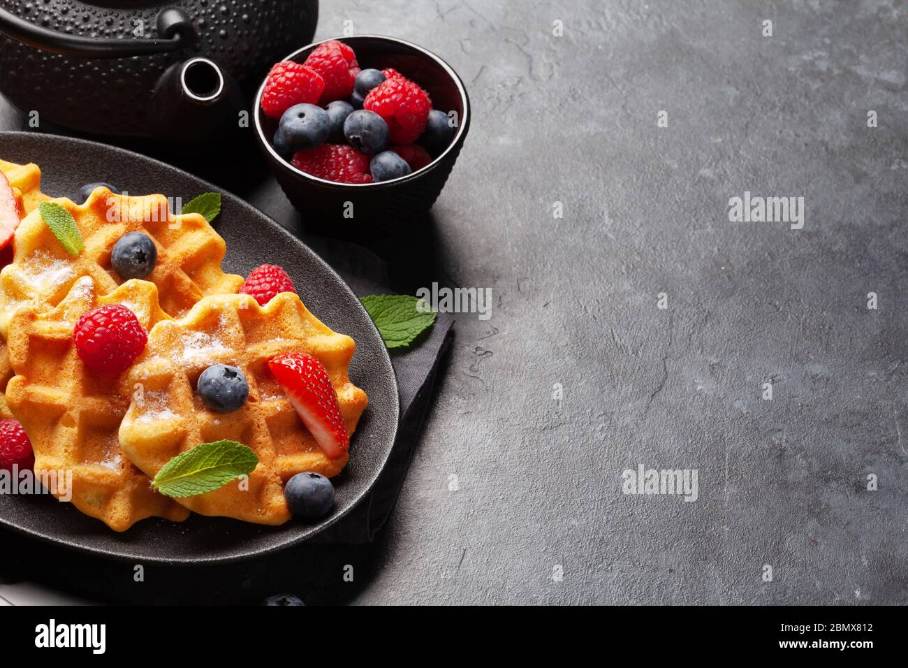Delicious belgian waffles with summer berries and breakfast tea. With ...