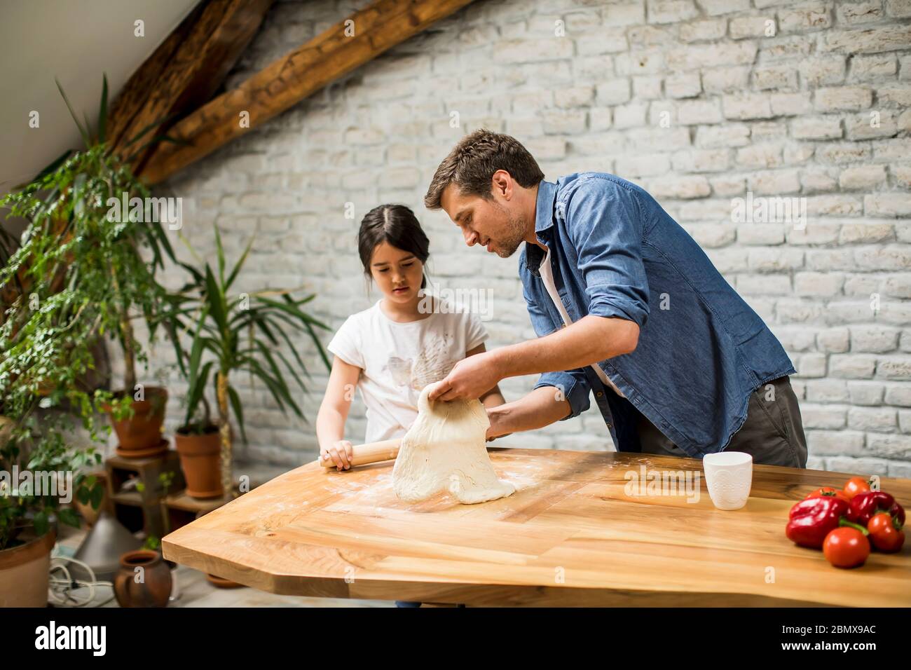 Young father and his cute daughter making dough at rustic home kitchen ...