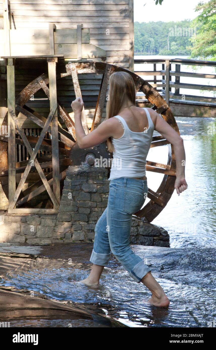 Pretty blond woman outside by a water wheel Stock Photo - Alamy