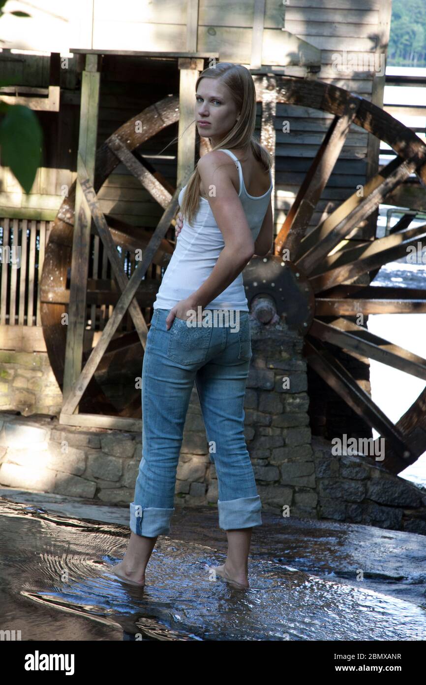 Pretty blond woman outside by a water wheel Stock Photo - Alamy