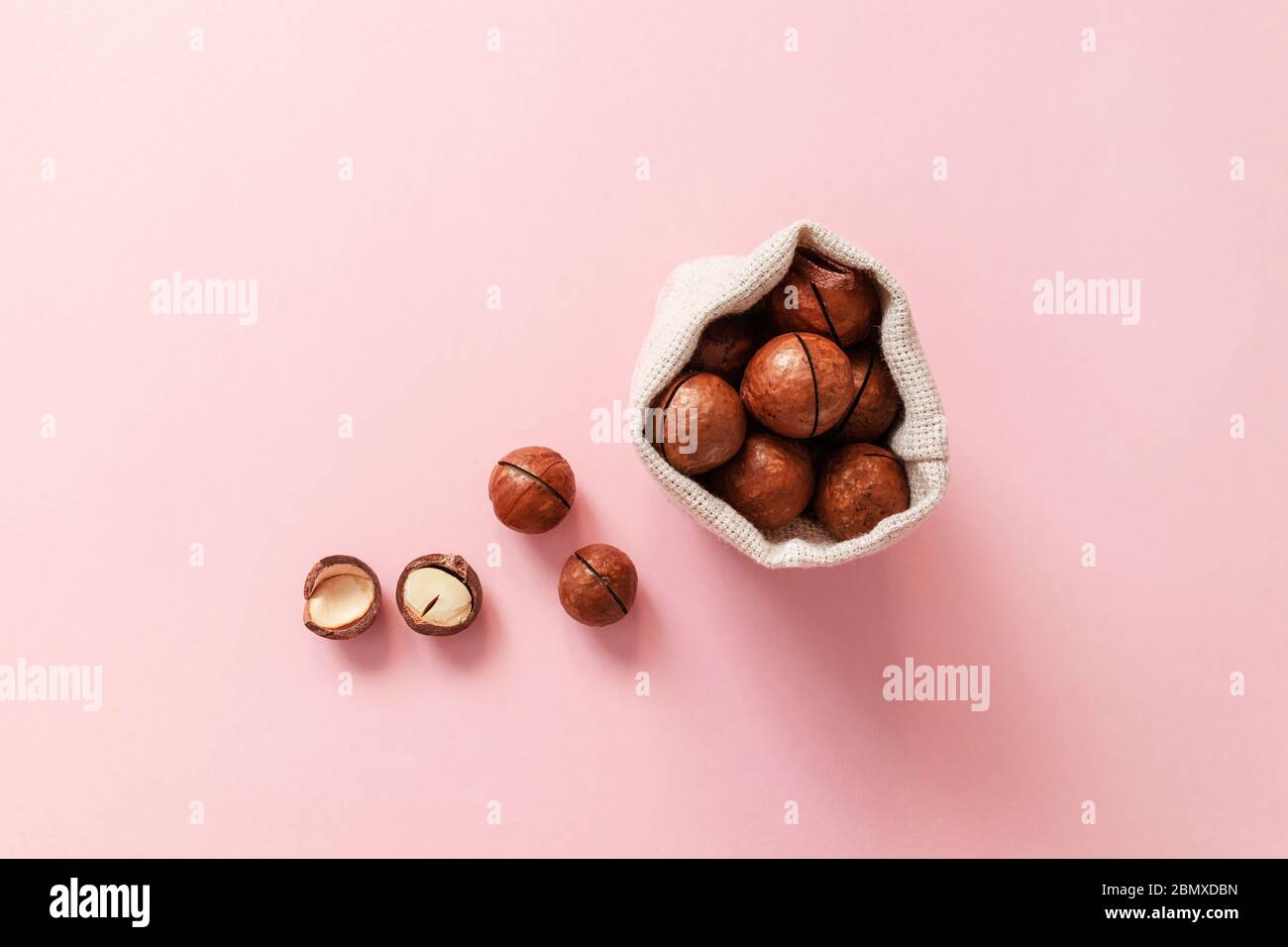Top view of macadamia nuts in burlap sack on pink background. Can be ...