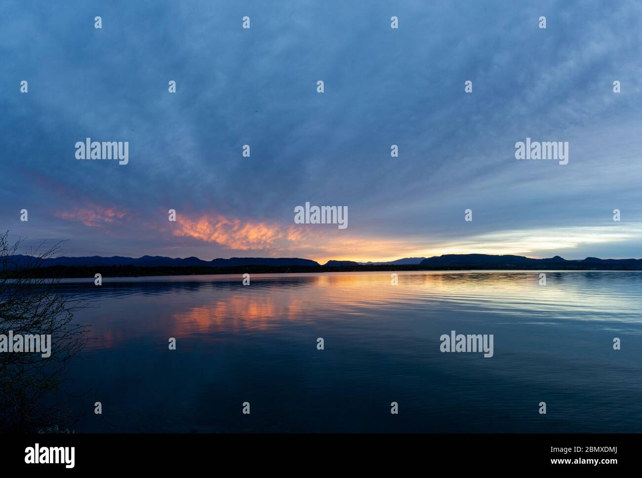The sun rising over a lake with the colors of sunrise reflecting off ...