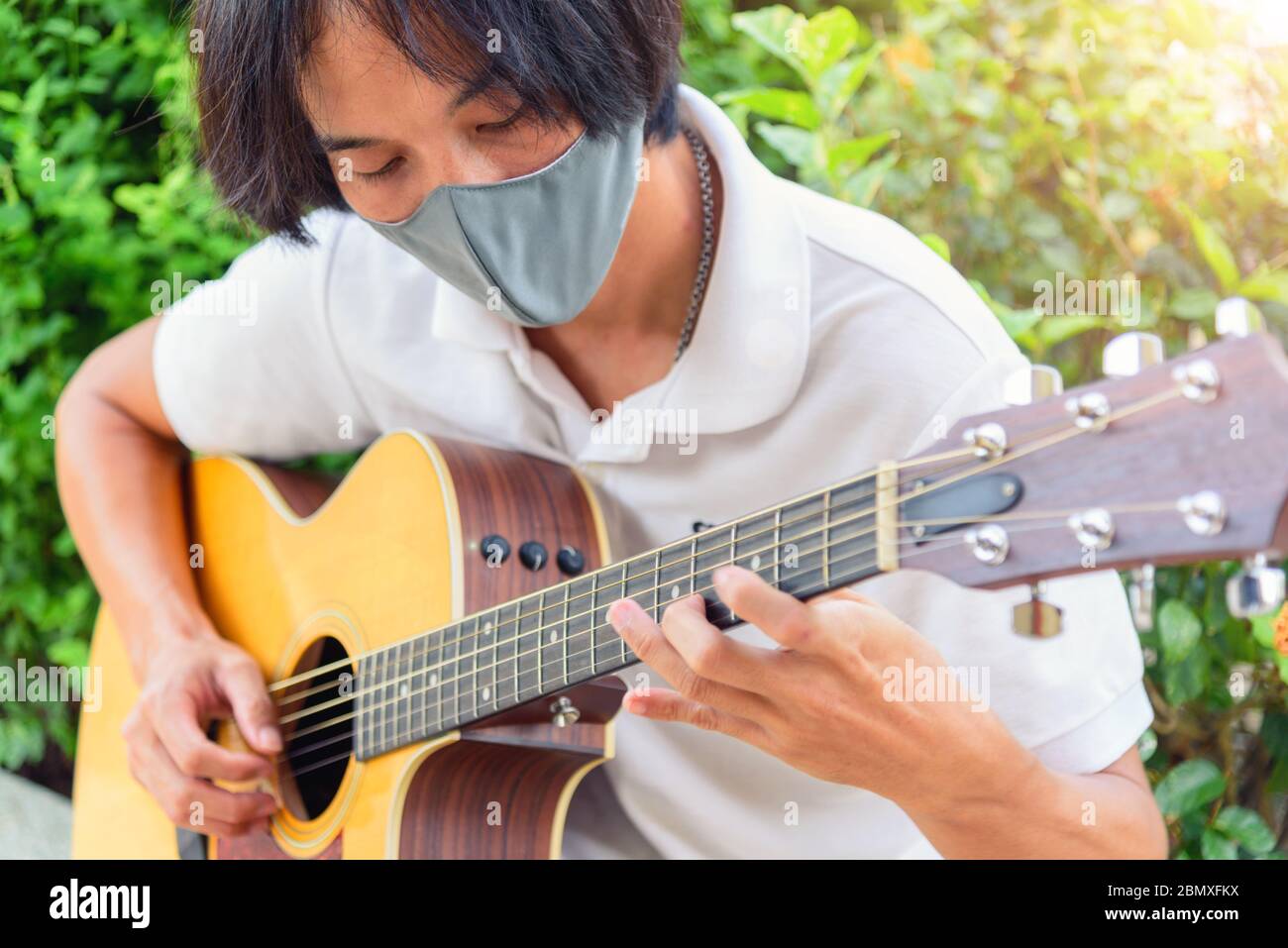 The man wear mask and playing guitar in the park / wear mask and ...