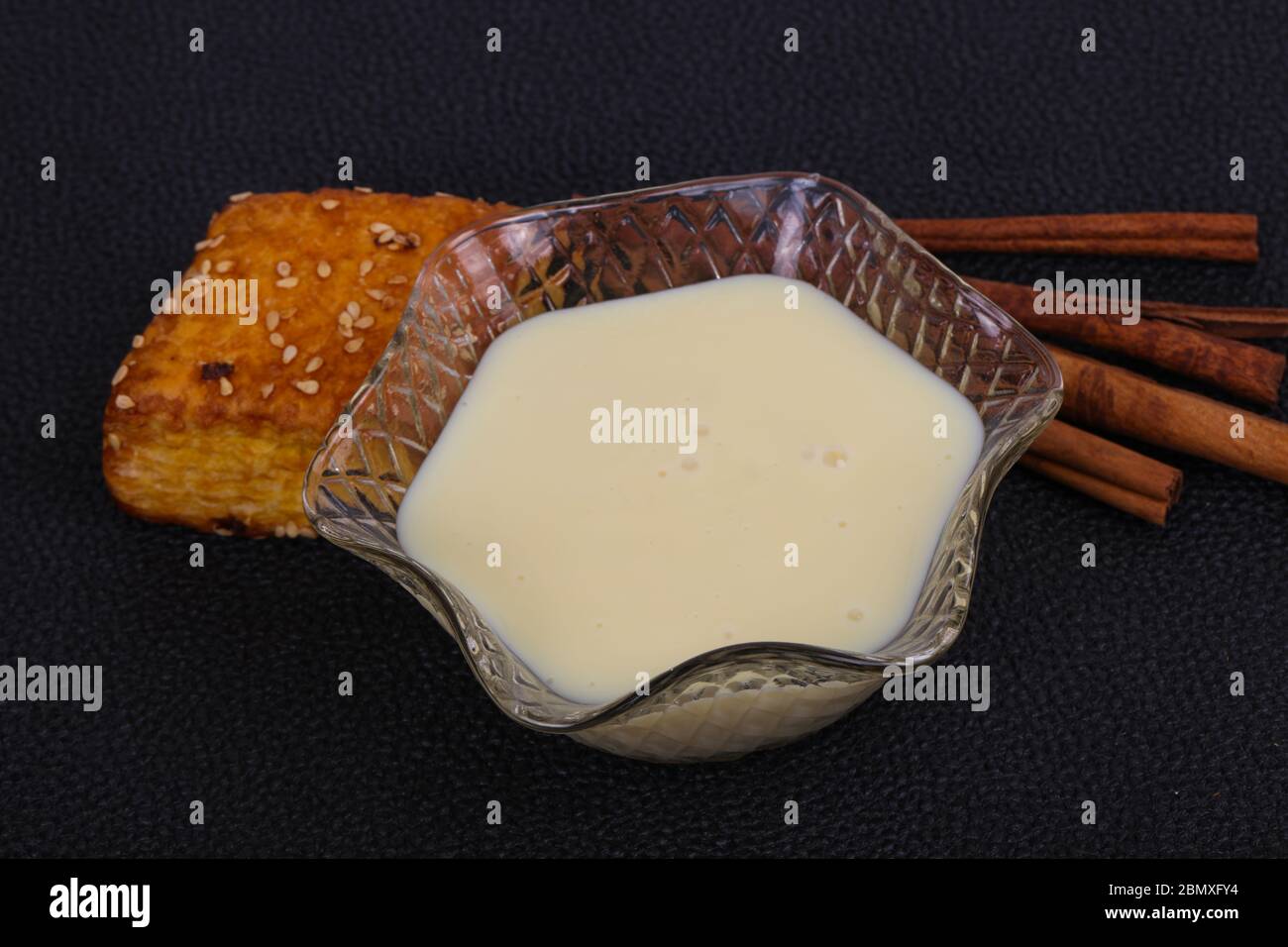 Condenced milk in the bowl with sinnamon sticks and pastry Stock Photo ...