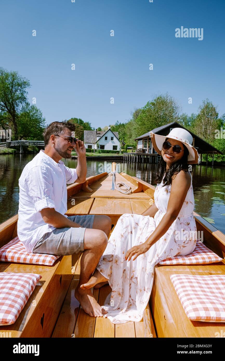 Giethoorn Netherlands couple visit the village with a boat ,view of famous village with canals ...
