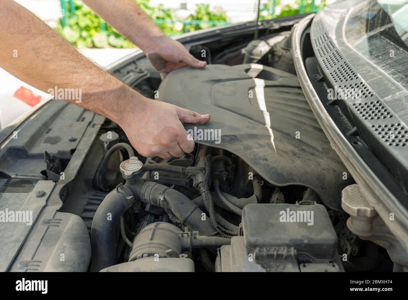 Auto mechanic works in the garage. Repair. Removing engine cover for ...