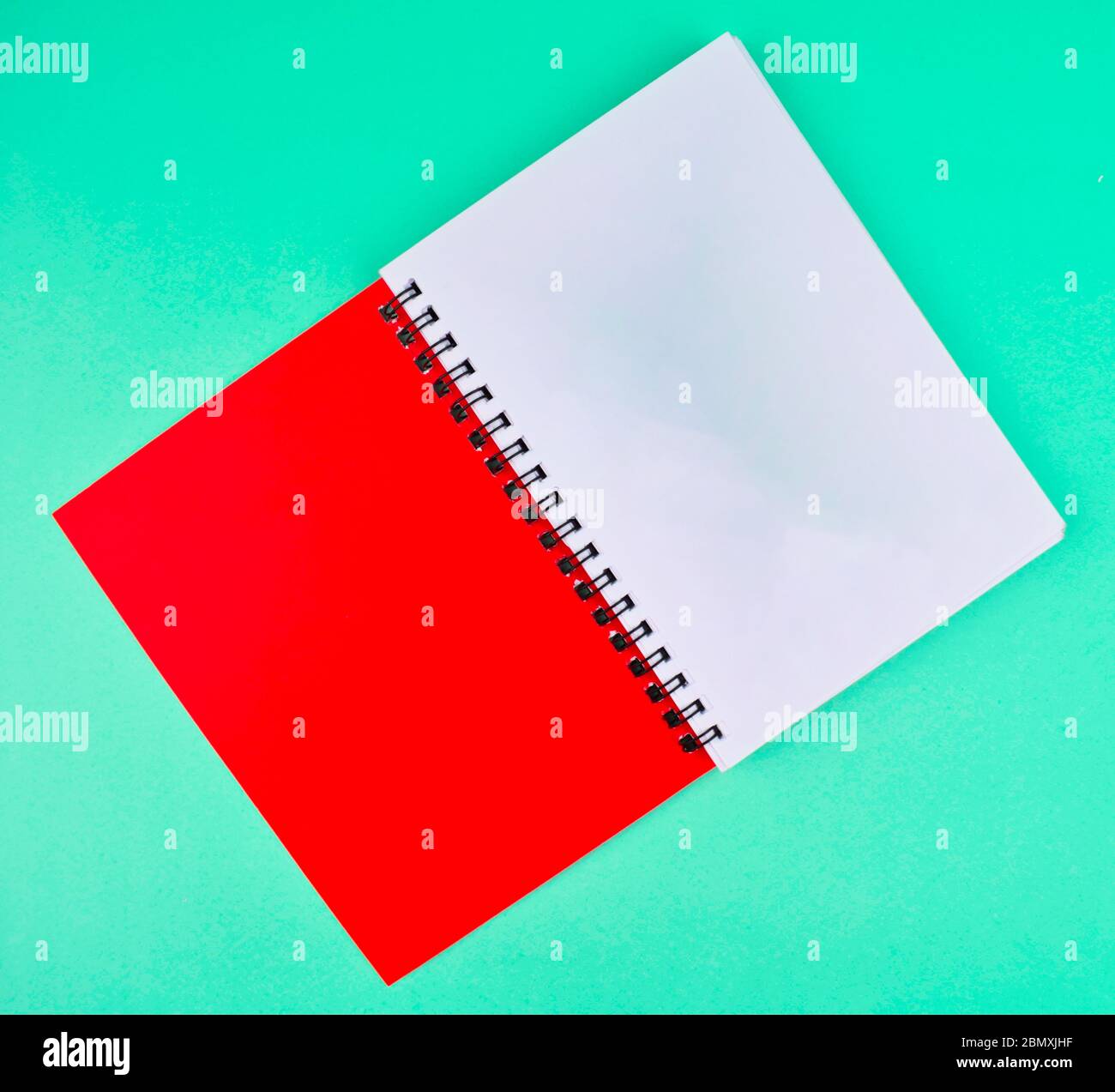 One red colored note paper diary placed on an isolated light blue paper ...